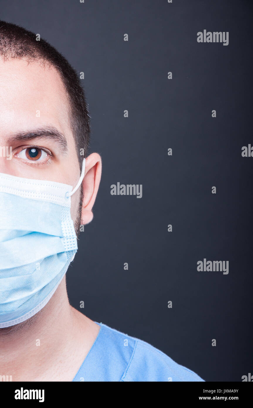 Close-up half face of doctor wearing scrubs and sterile mask on black ...