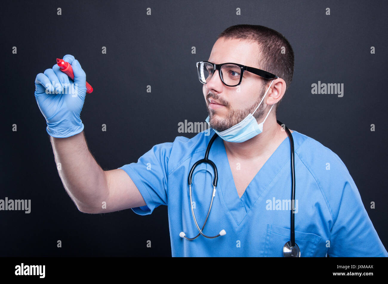 Doctor or medic wearing glasses writing on invisible board with red ...