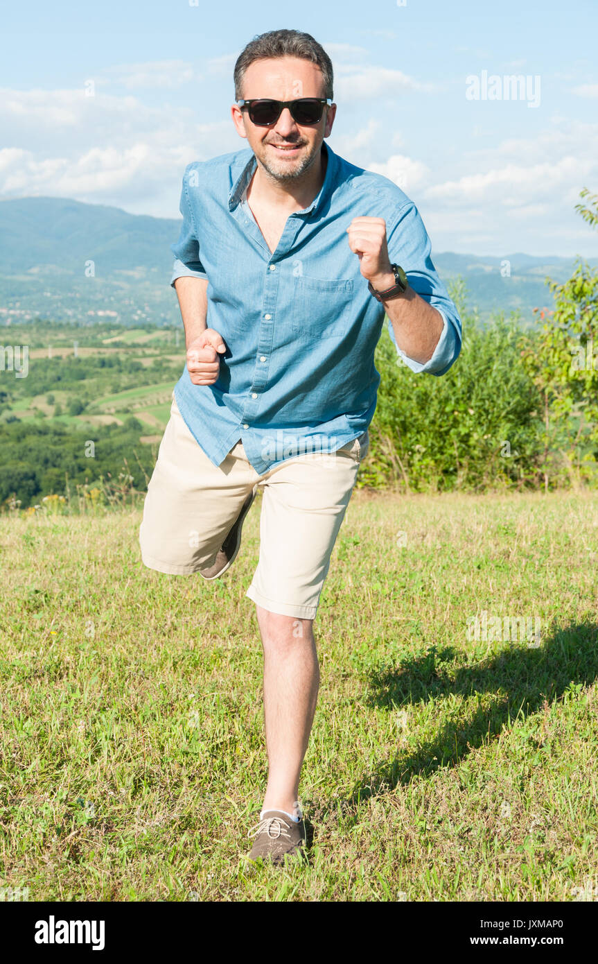 Cheerful hipster guy running on sunny meadow spending his time in ...