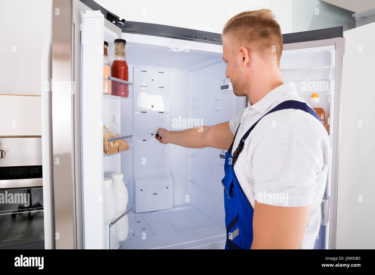 Young Male Repairman Fixing Refrigerator In Kitchen Stock Photo - Alamy