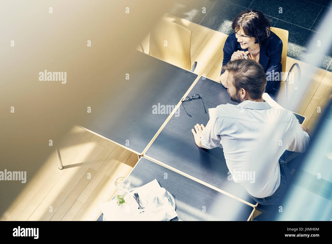 High angle window view of businesswoman and man looking over in office ...