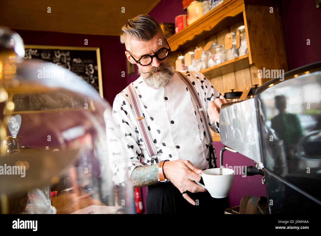 Quirky vintage senior man preparing coffee behind cafe counter Stock ...