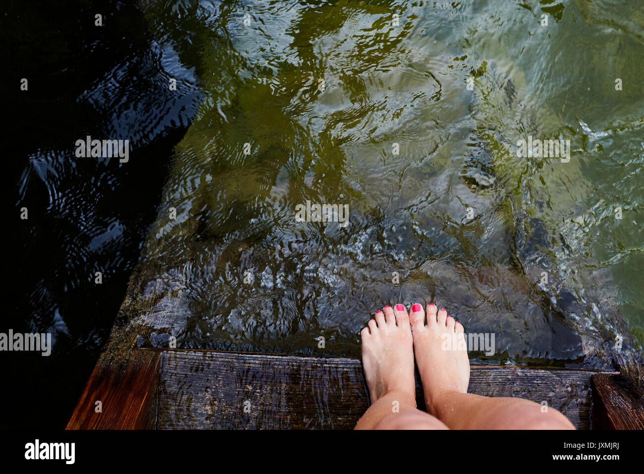 Woman's feet at edge of wooden pier by water Stock Photo - Alamy