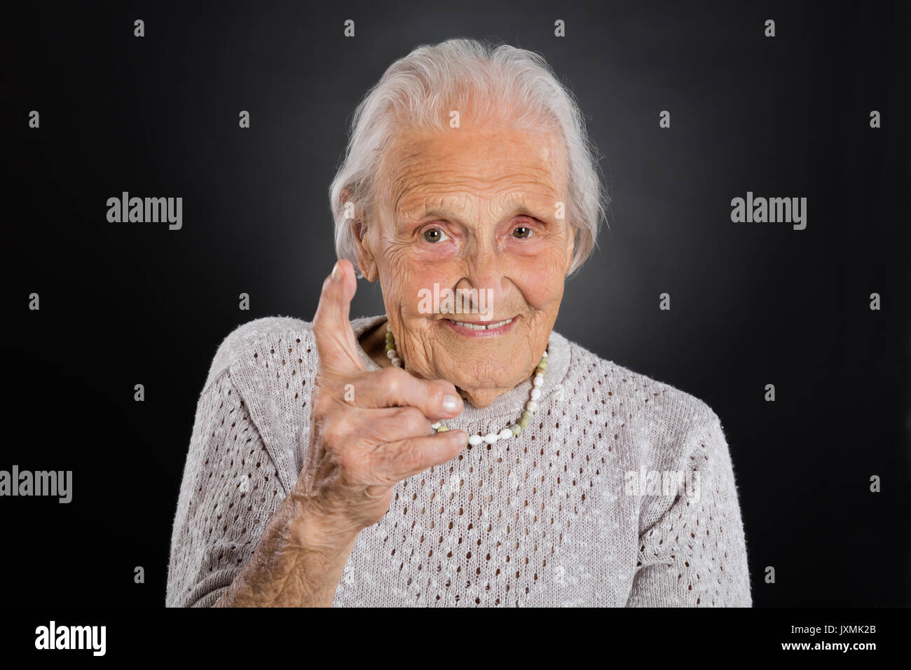 Portrait Of A Smiling Elder Woman Waving Her Finger Over Grey ...