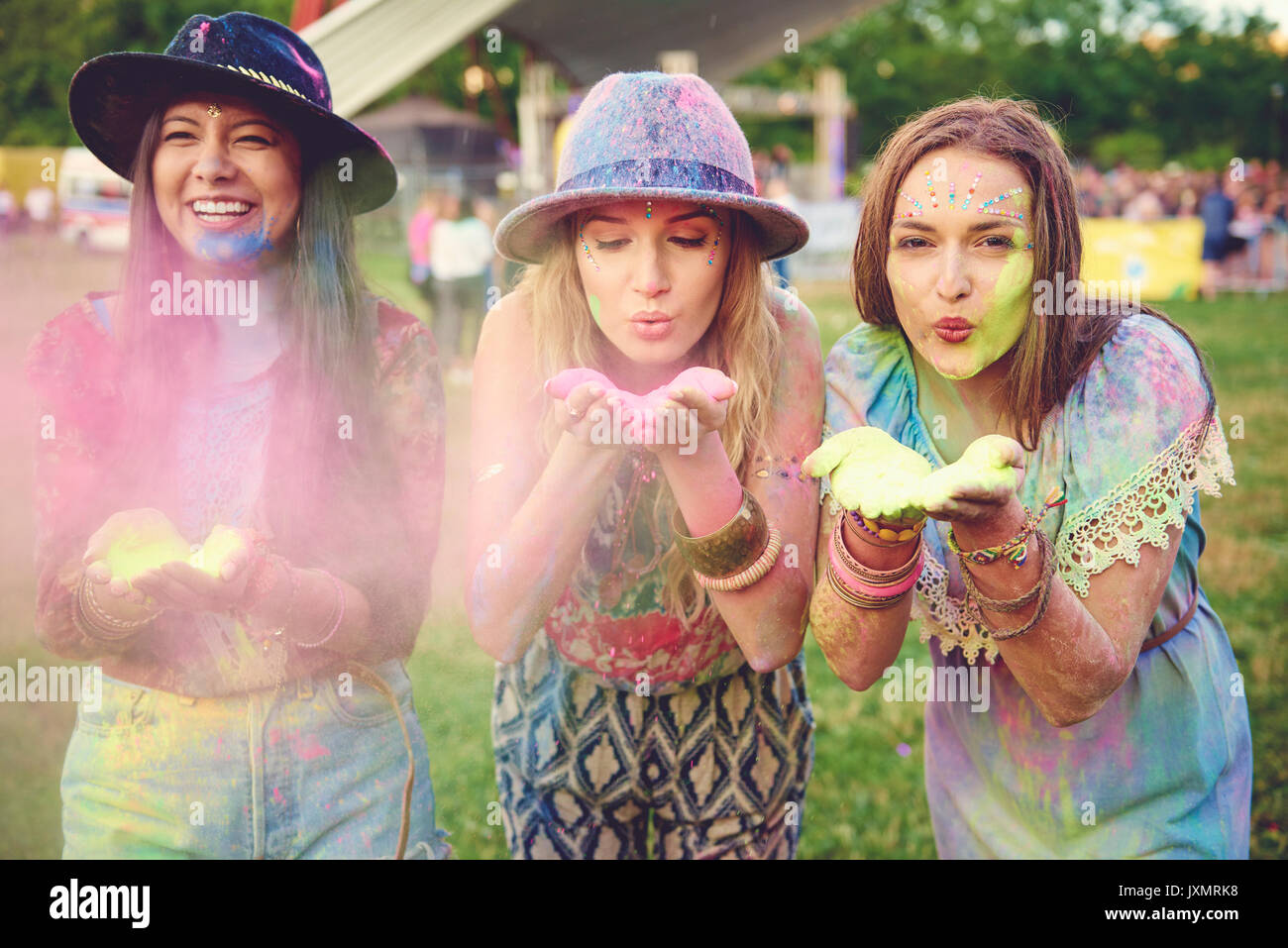Three young women blowing coloured chalk powder at festival Stock Photo ...