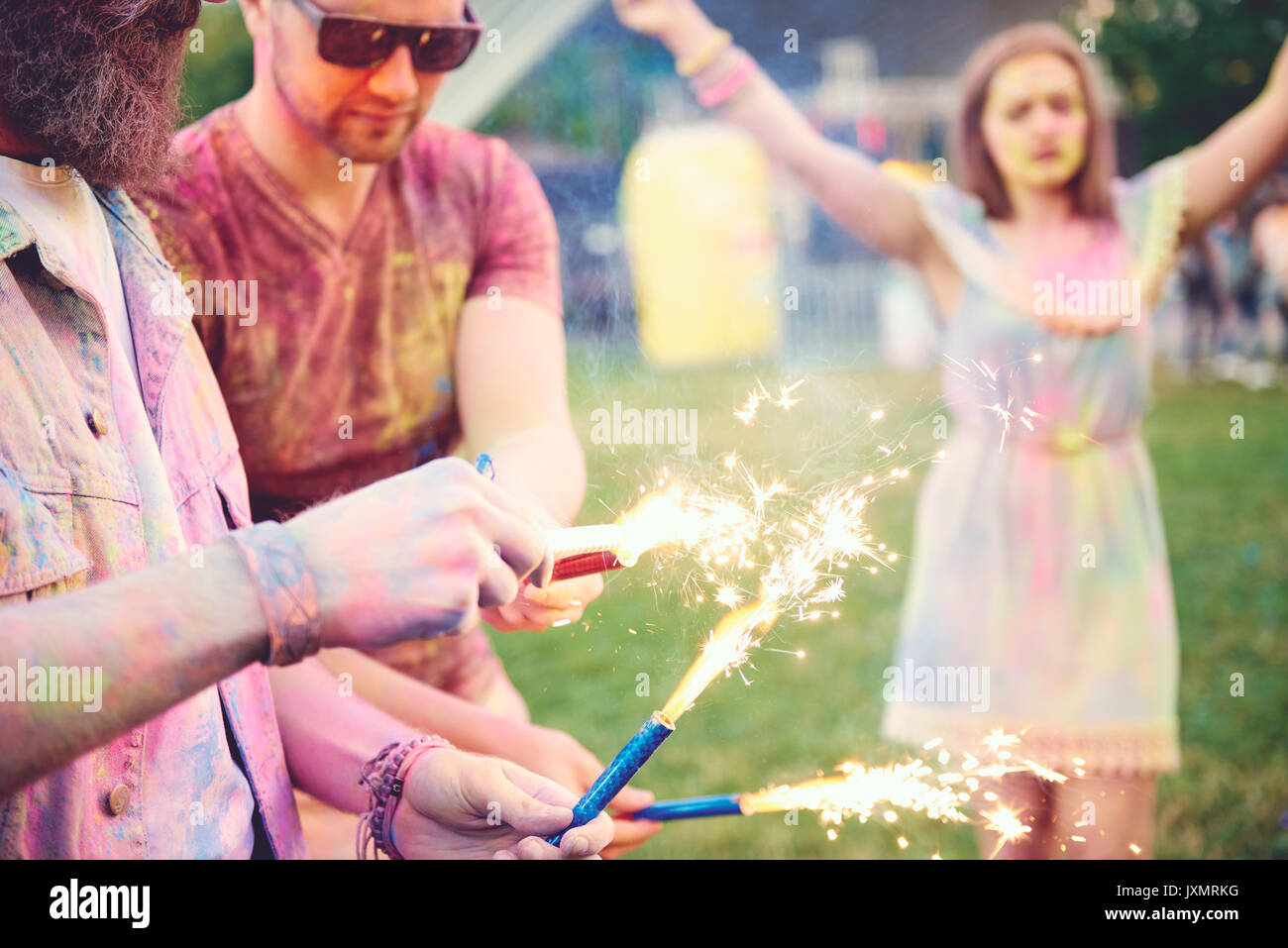 Young men covered in coloured chalk powder holding sparklers at ...