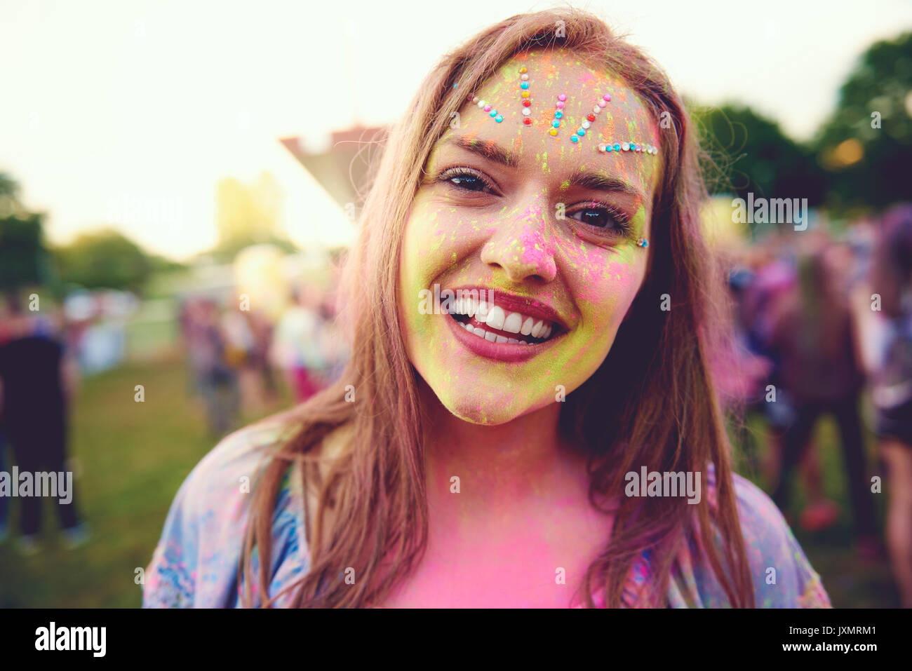 Portrait of young boho woman with face covered in coloured chalk powder ...