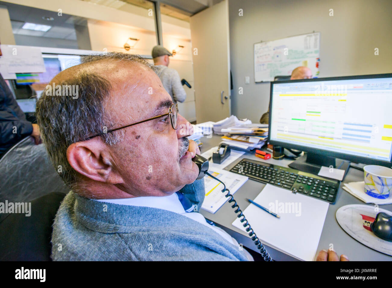 Over shoulder view of manager making telephone call at office desk ...