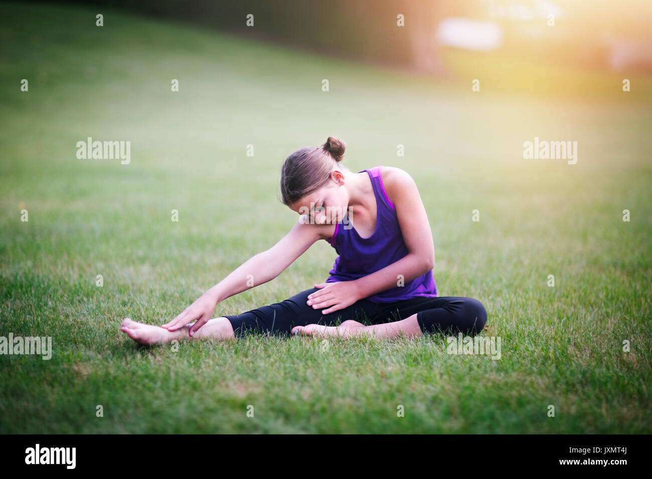 Girl stretching on grass Stock Photo - Alamy