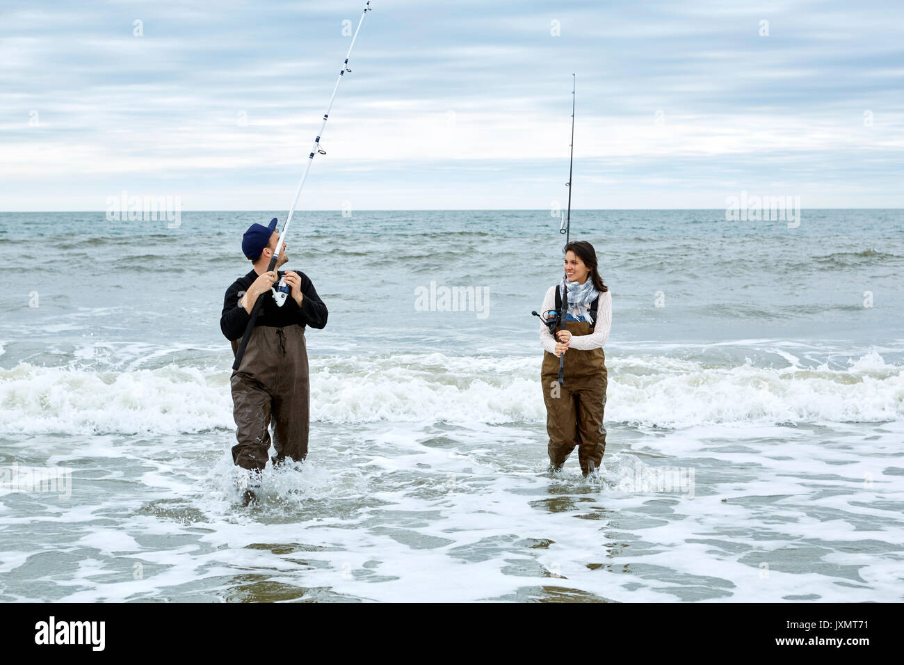 Young couple in waders sea fishing knee deep in water Stock Photo - Alamy