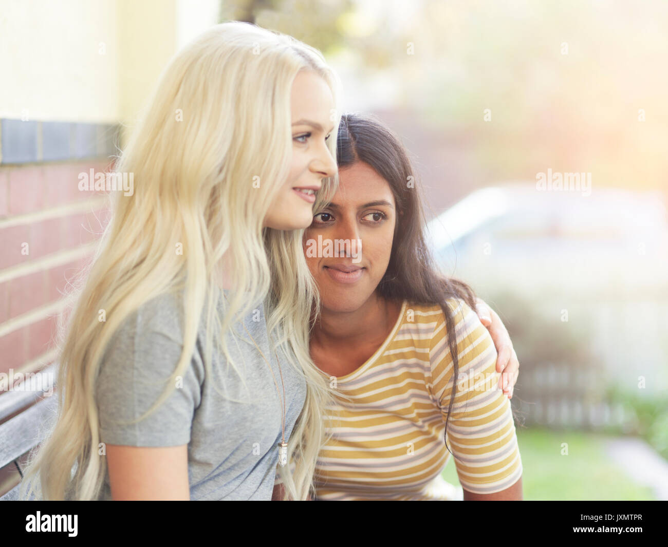 Young woman sitting on bench, hugging friend sitting beside her Stock ...