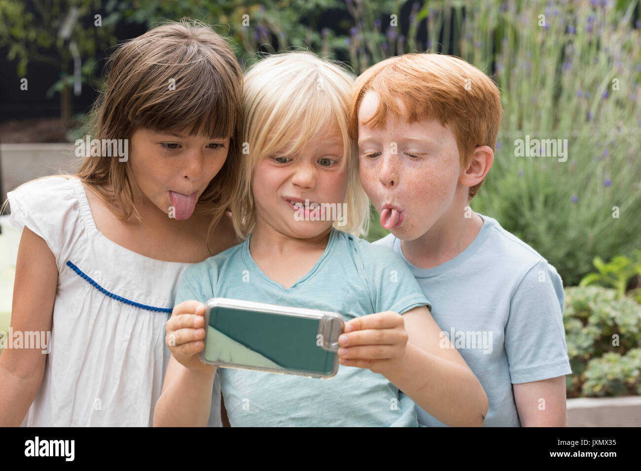 Children sticking out tongue taking selfie Stock Photo - Alamy