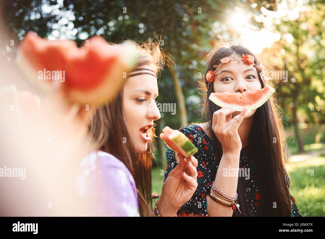 Young boho women making smiley face with melon slice at festival Stock ...