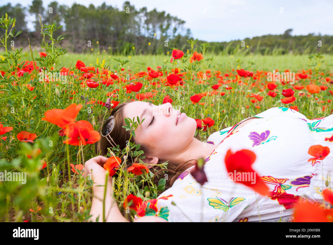 Woman lying in poppy field with eyes closed, Palma de Mallorca, Islas ...