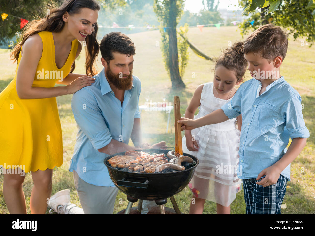 Father and son preparing meat on charcoal barbecue grill during Stock ...