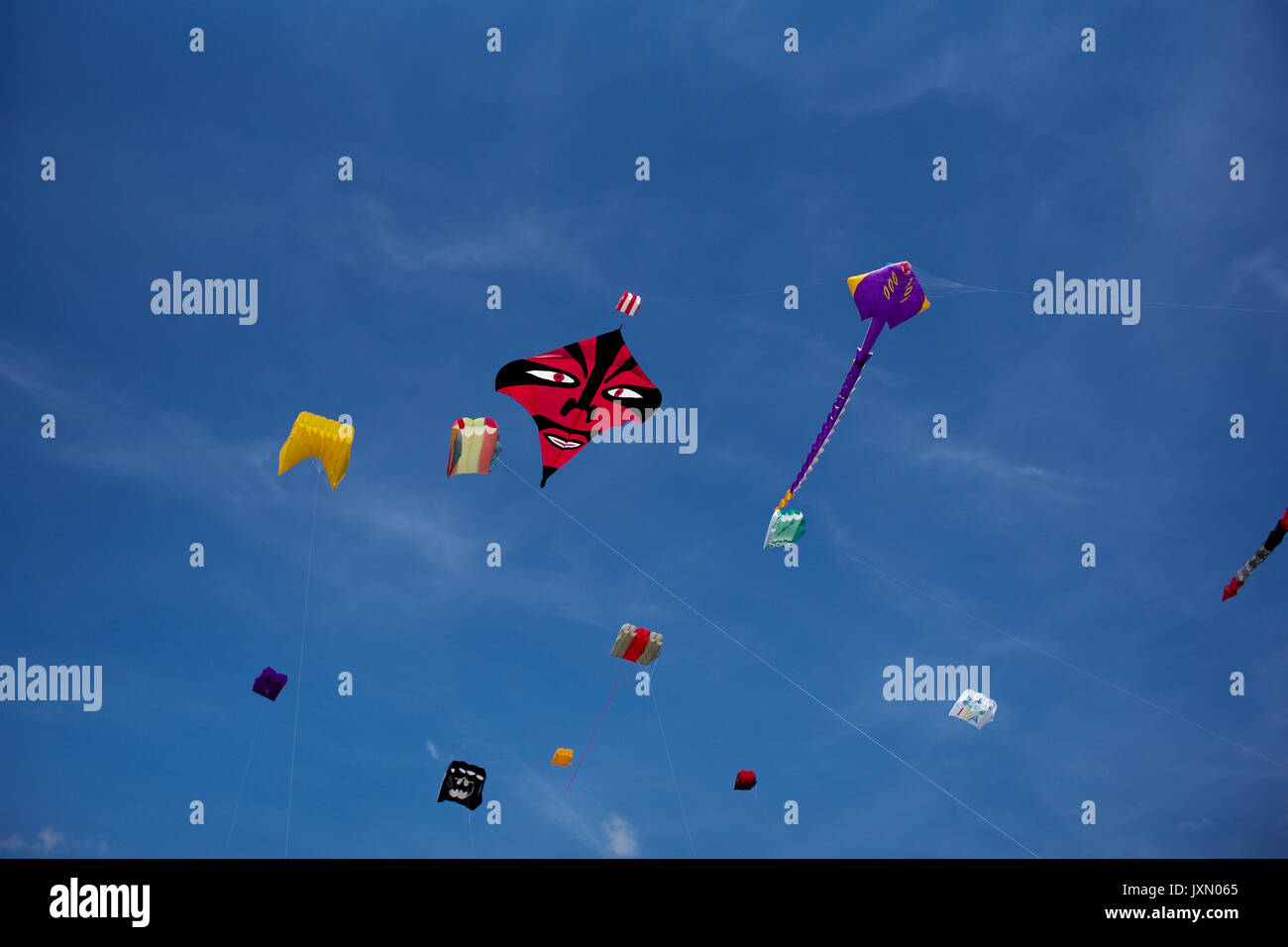 kites flying against a blue sky with one having a distinctive scary ...