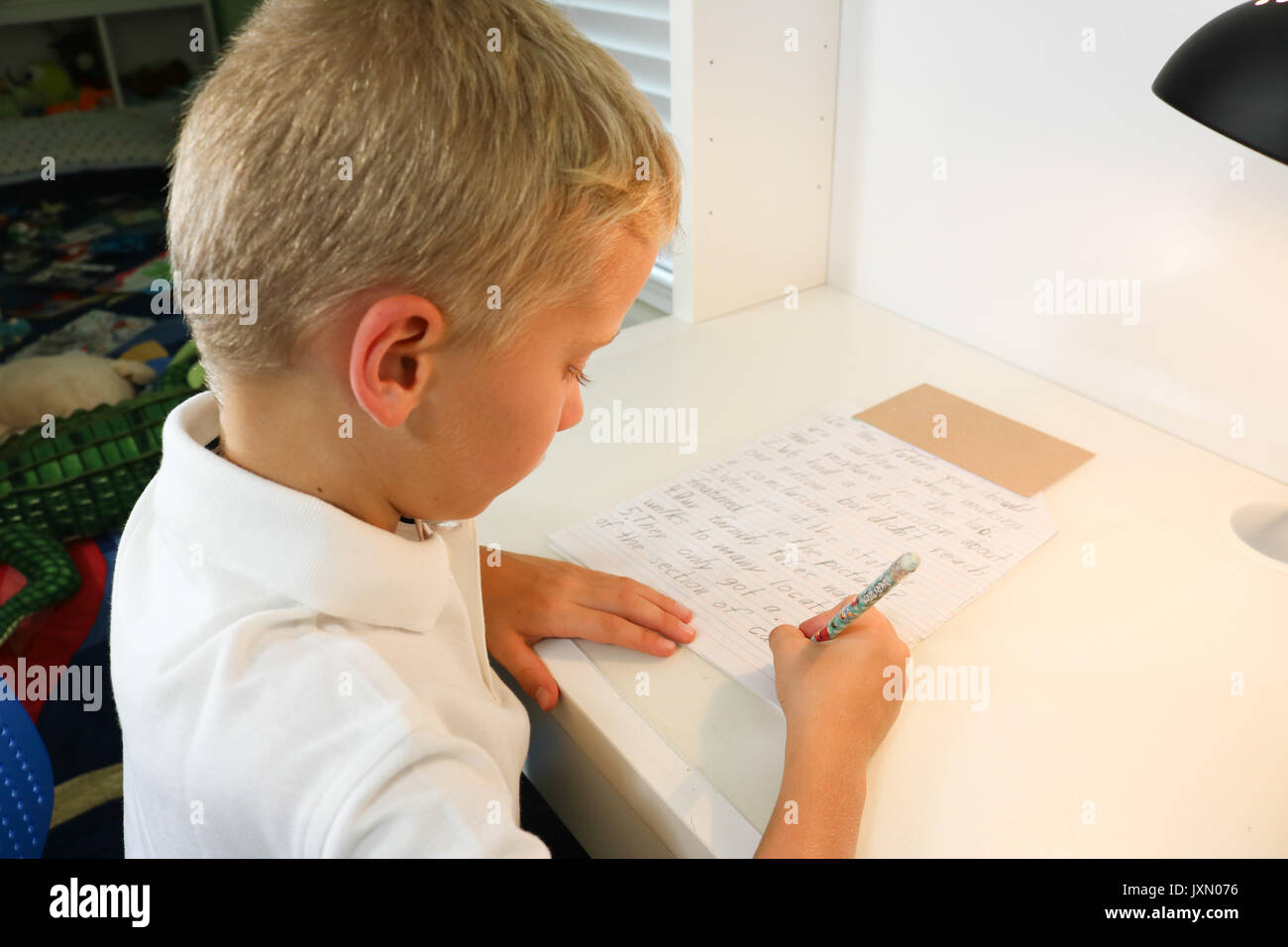 Young boy doing writing homework at his desk Stock Photo - Alamy