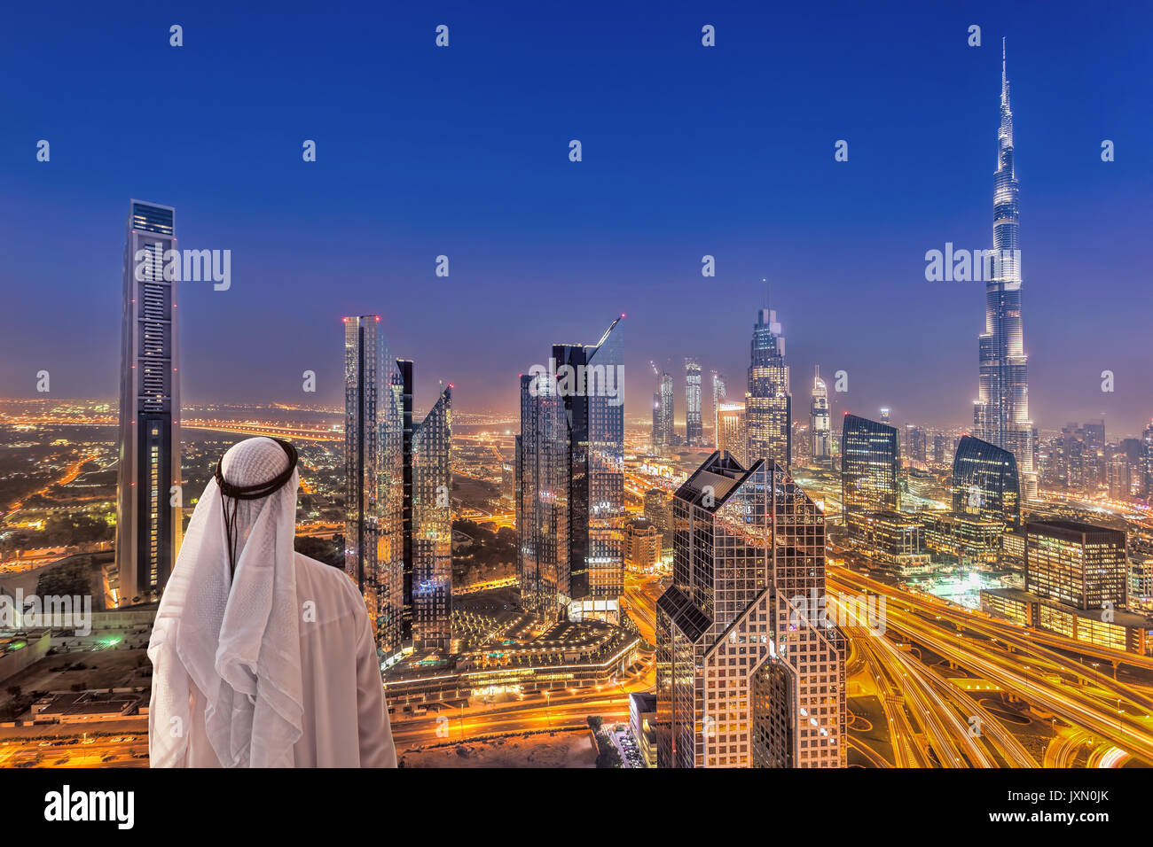 Arabian man watching night cityscape of Dubai with modern futuristic ...
