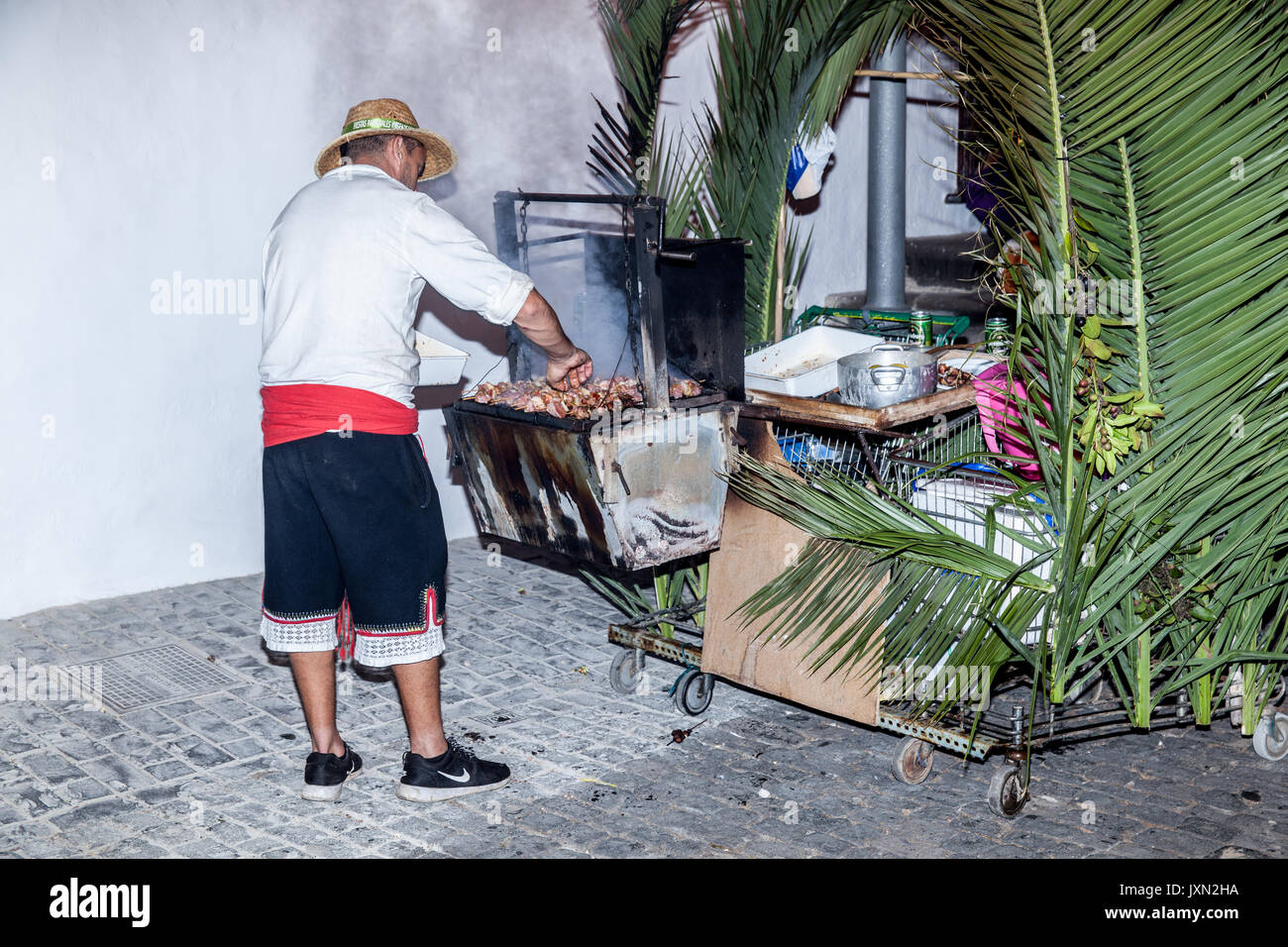spanish middle-aged man dressed in traditional peasant costume roasting ...