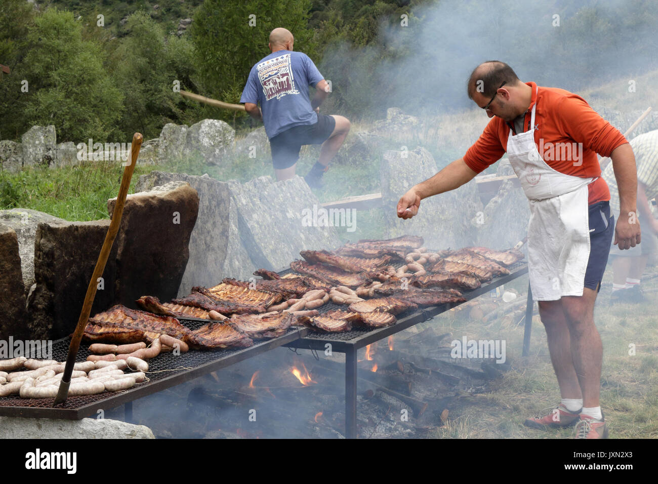 A man throwing salt on meat being grilled and smoked on a firewood and ...