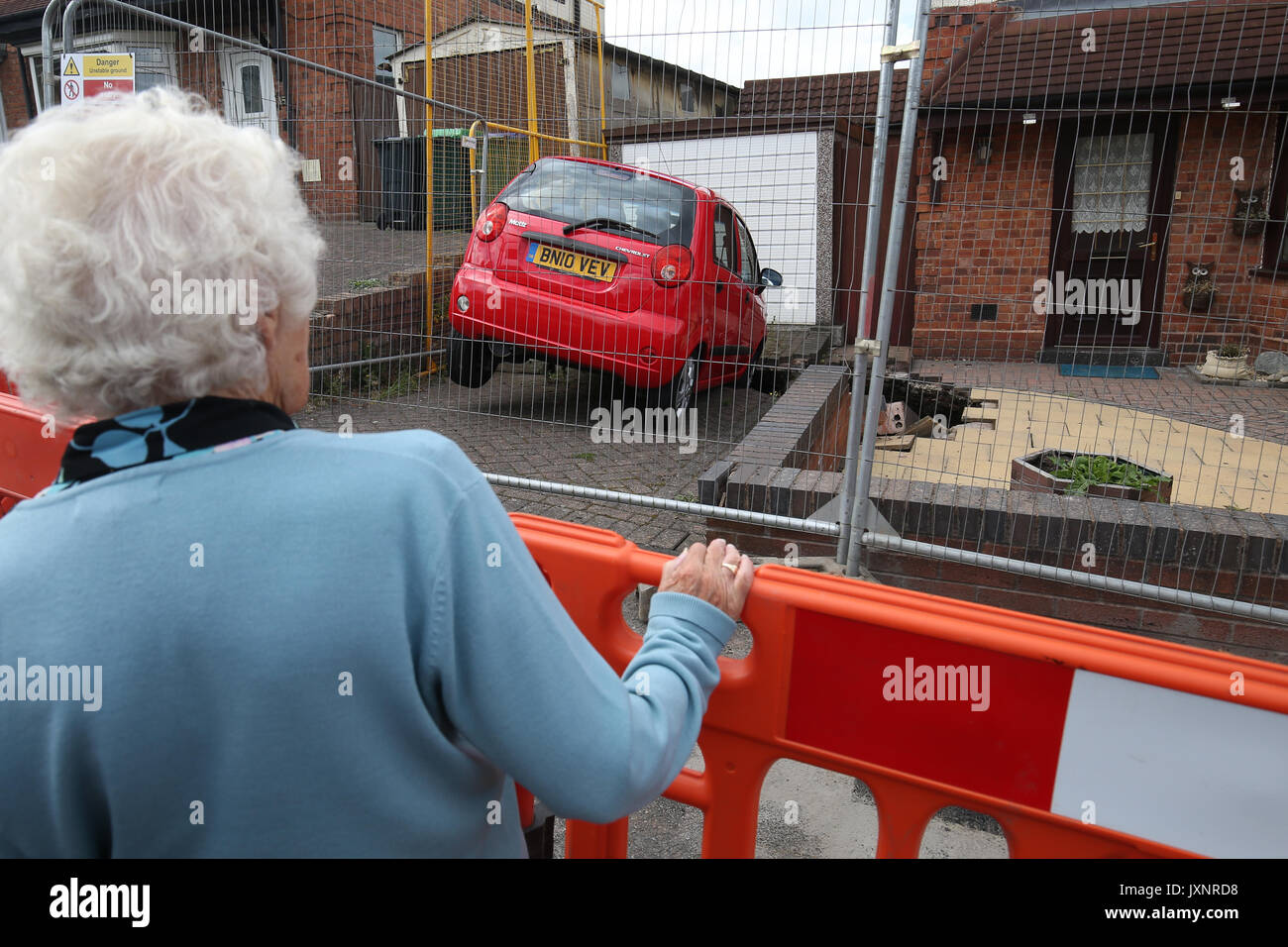 An lady looks at a huge sinkhole which has opened up beneath a driveway ...