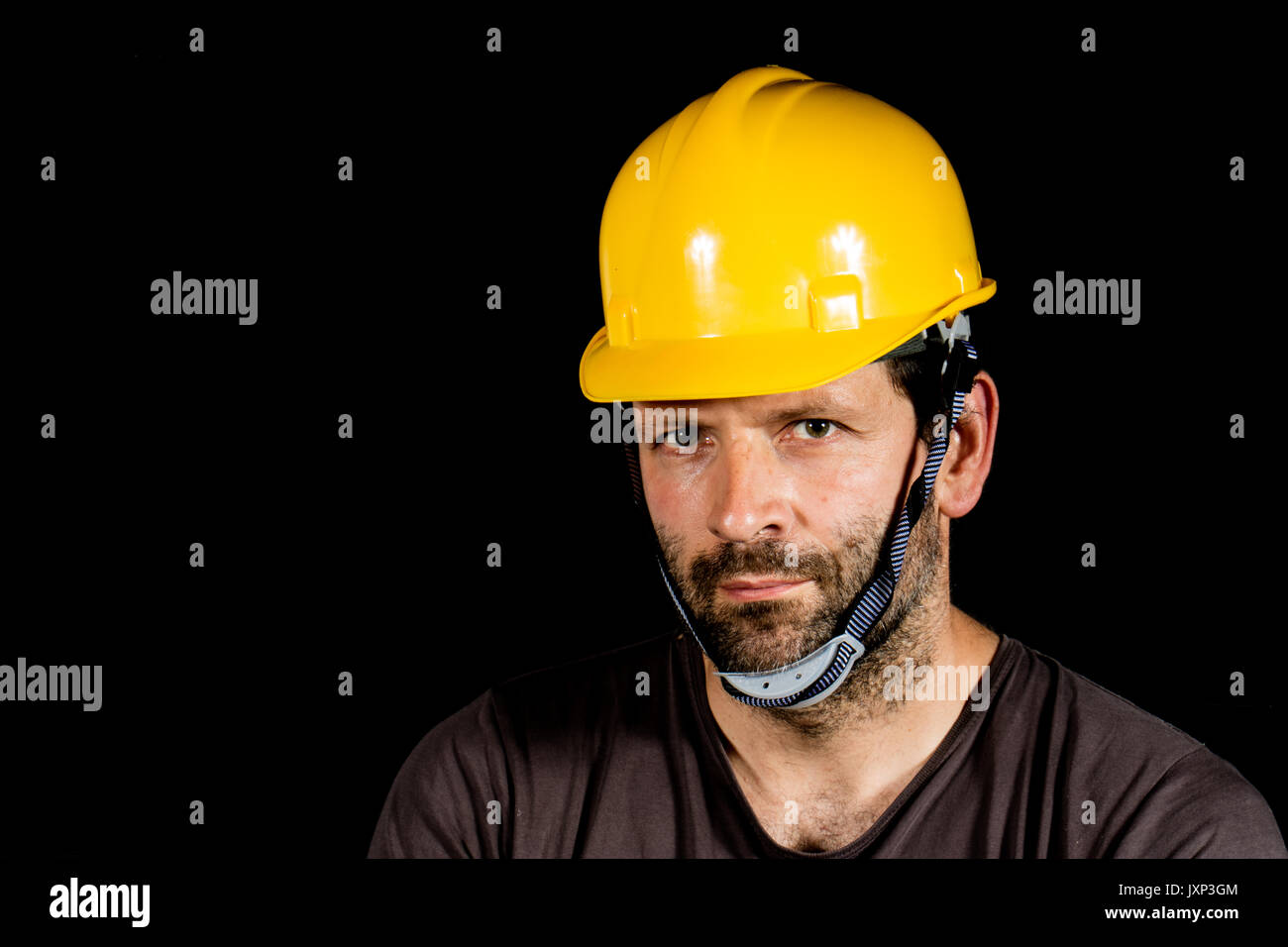 Worker, employee in a helmet. Black beard, black background. Yellow ...