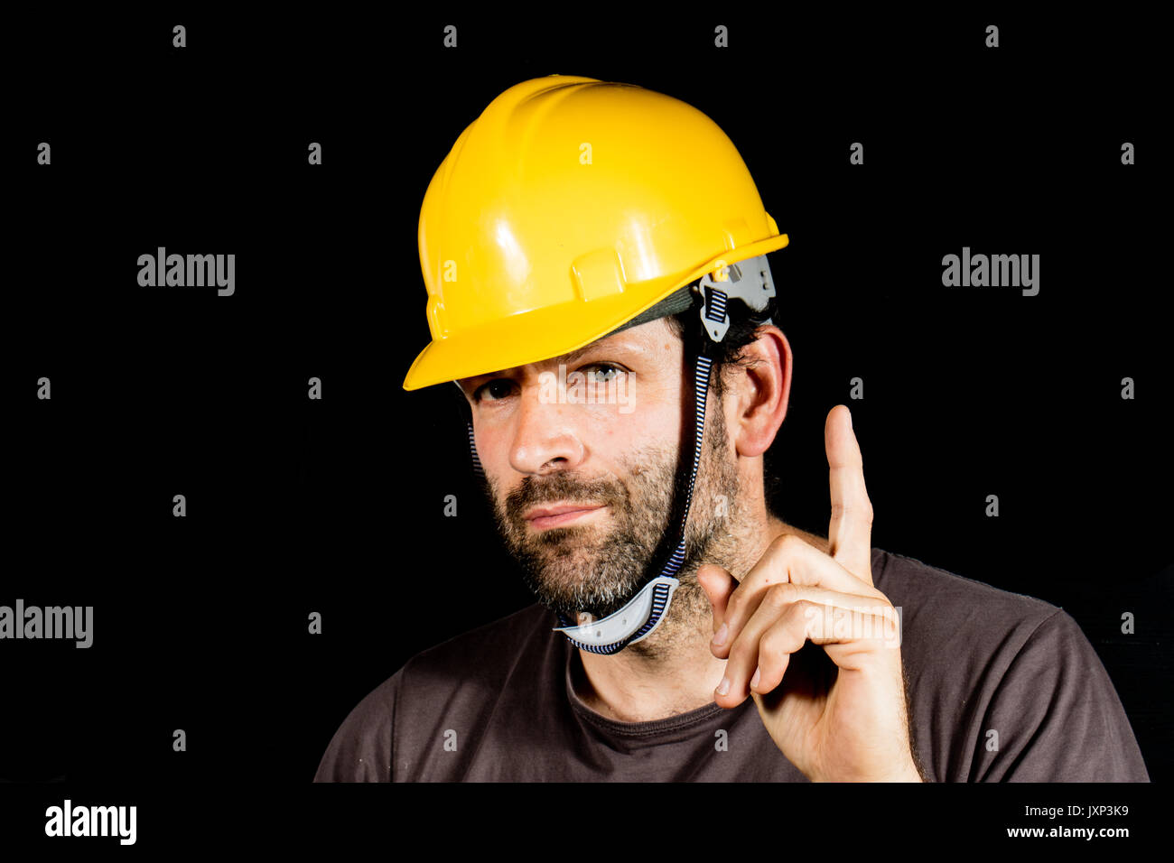 Worker, employee in a helmet. Black beard, black background. Yellow ...