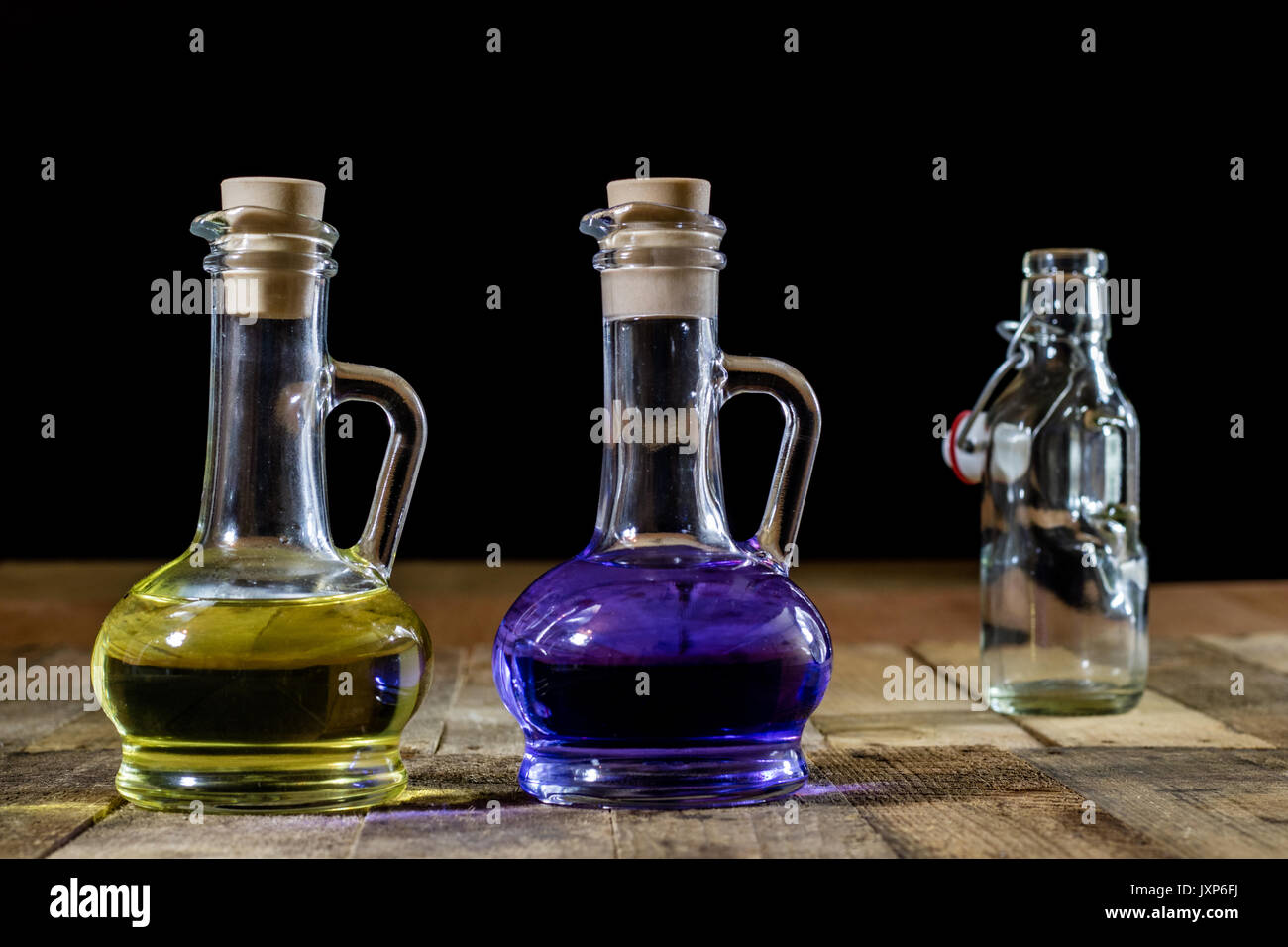Bottles of colored liquid on a wooden kitchen table. Wooden table ...