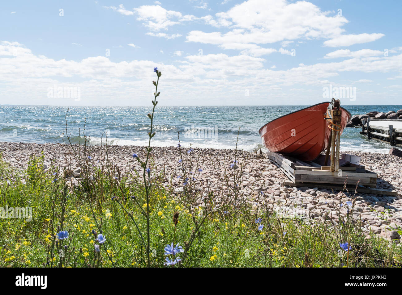 Landed red rowing boat by a colorful beach at the swedish island Oland ...