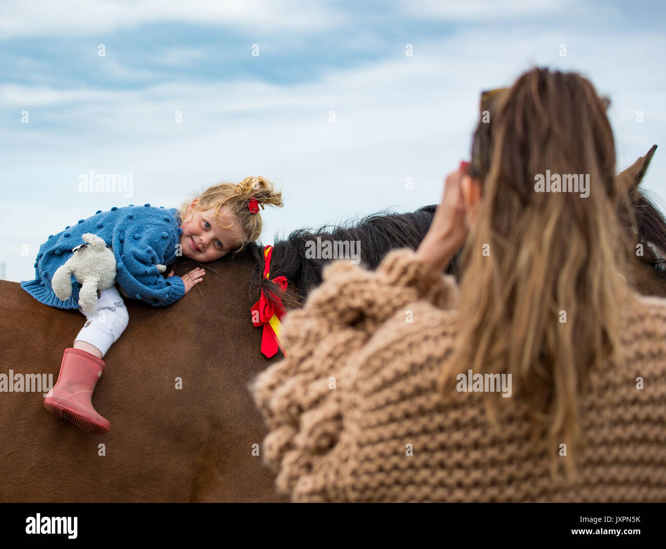 Little girl being photographed on a horse Stock Photo - Alamy