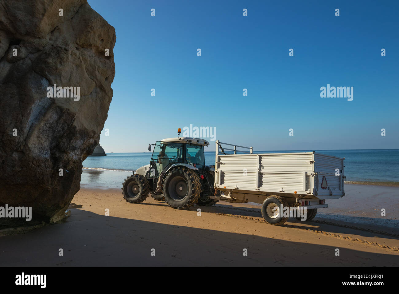 Tractor with trailer carry out beach maintenance on the ocean coast in ...