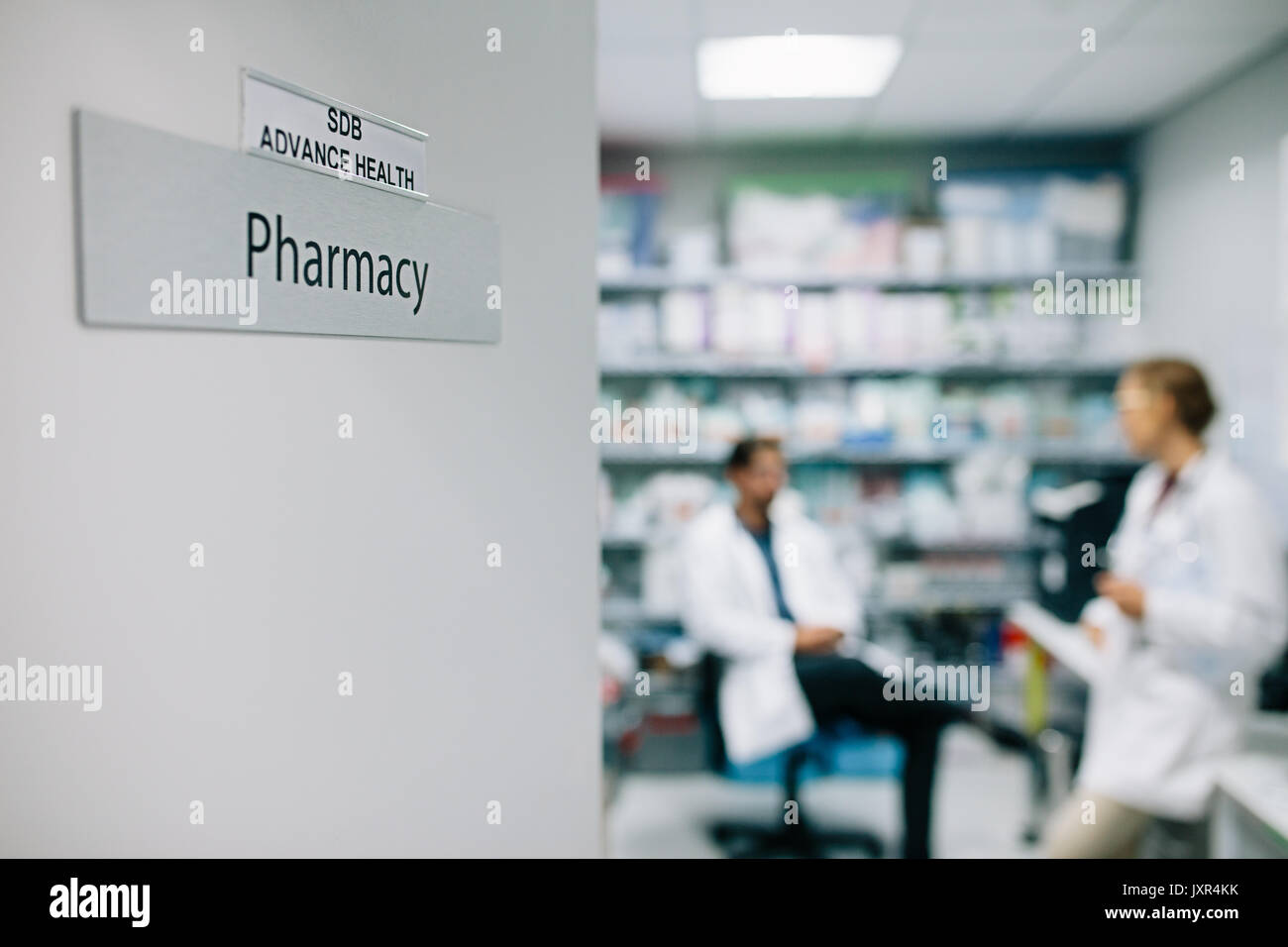 Pharmacists at the hospital pharmacy. Focus on pharmacy name plate on ...