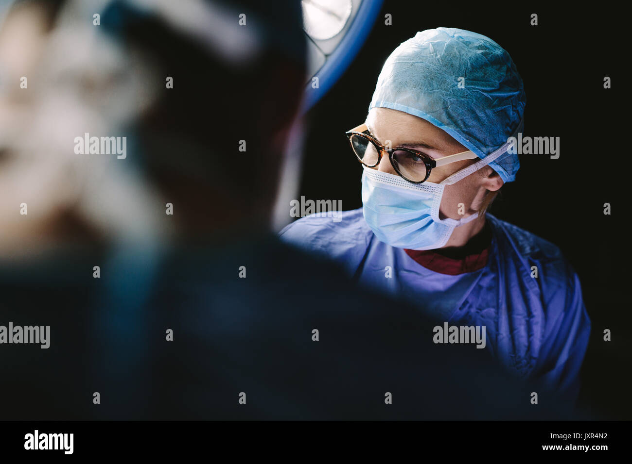 Surgeon wearing medical mask with medical team performing surgery in ...