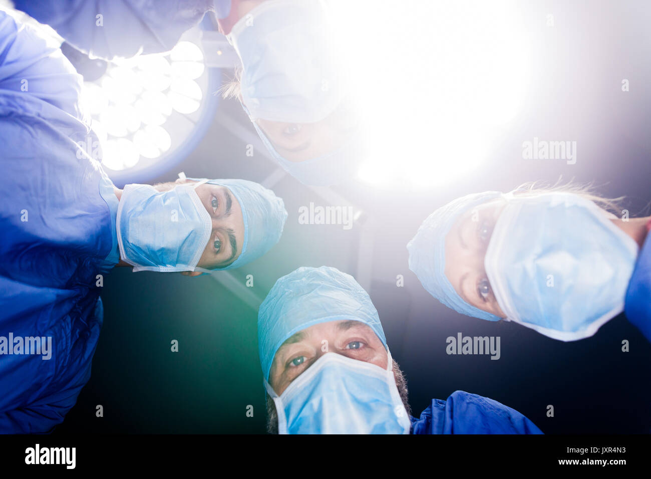 Team of doctors looking down at patient in operation room. Surgeons ...