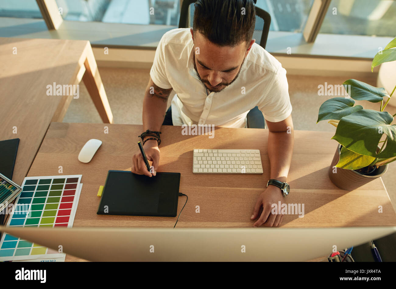 Top view shot of young man working in office using graphics tablet and ...