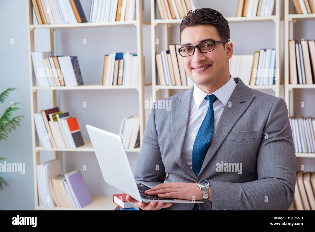 Businessman with a laptop working in the library Stock Photo - Alamy