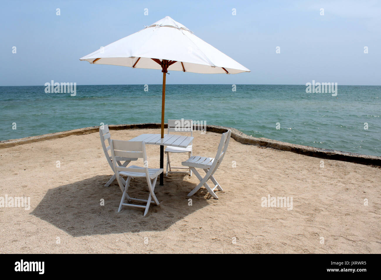 View of four chairs and umbrella on the beach Stock Photo - Alamy
