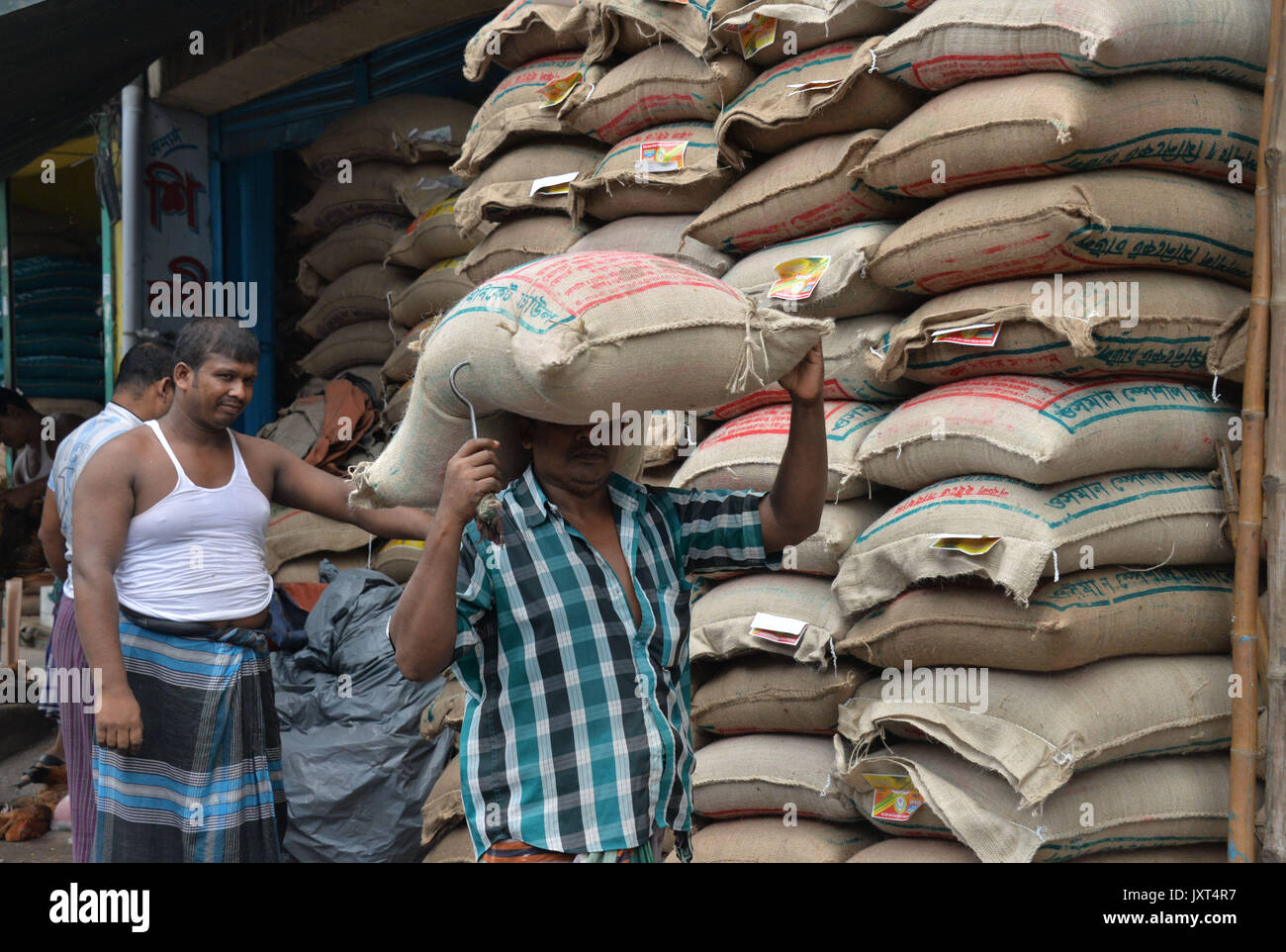 Dhaka. 17th Aug, 2017. A laborer carries a large sack of rice in Dhaka ...