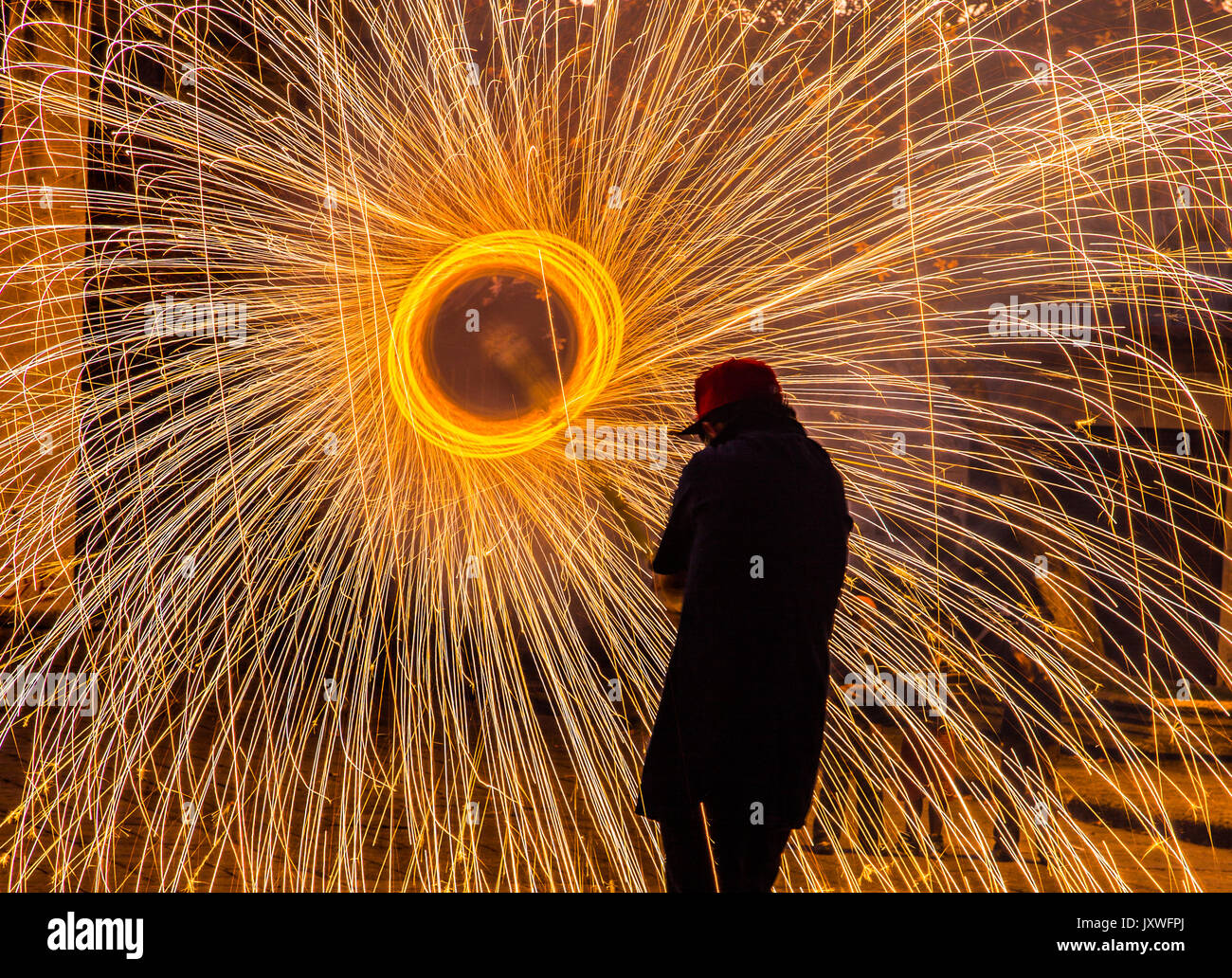 This man is holding a 6 foot pole with spinning fireworks on the end ...