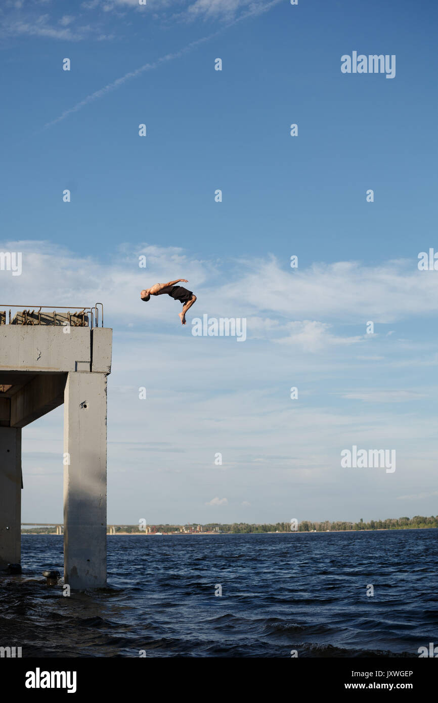 A man is jumping into the sea from a high pier. Adrenaline and extreme ...