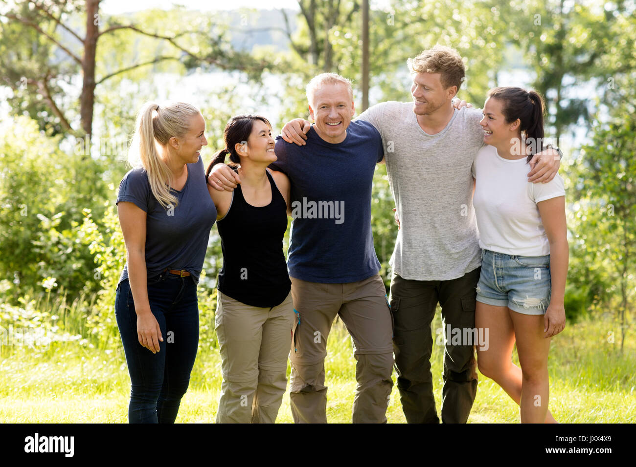 Man Standing With Arms Around Friends In Forest Stock Photo - Alamy