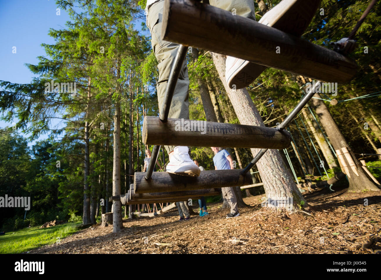 Young Man Crossing Log Bridge In Forest Stock Photo - Alamy