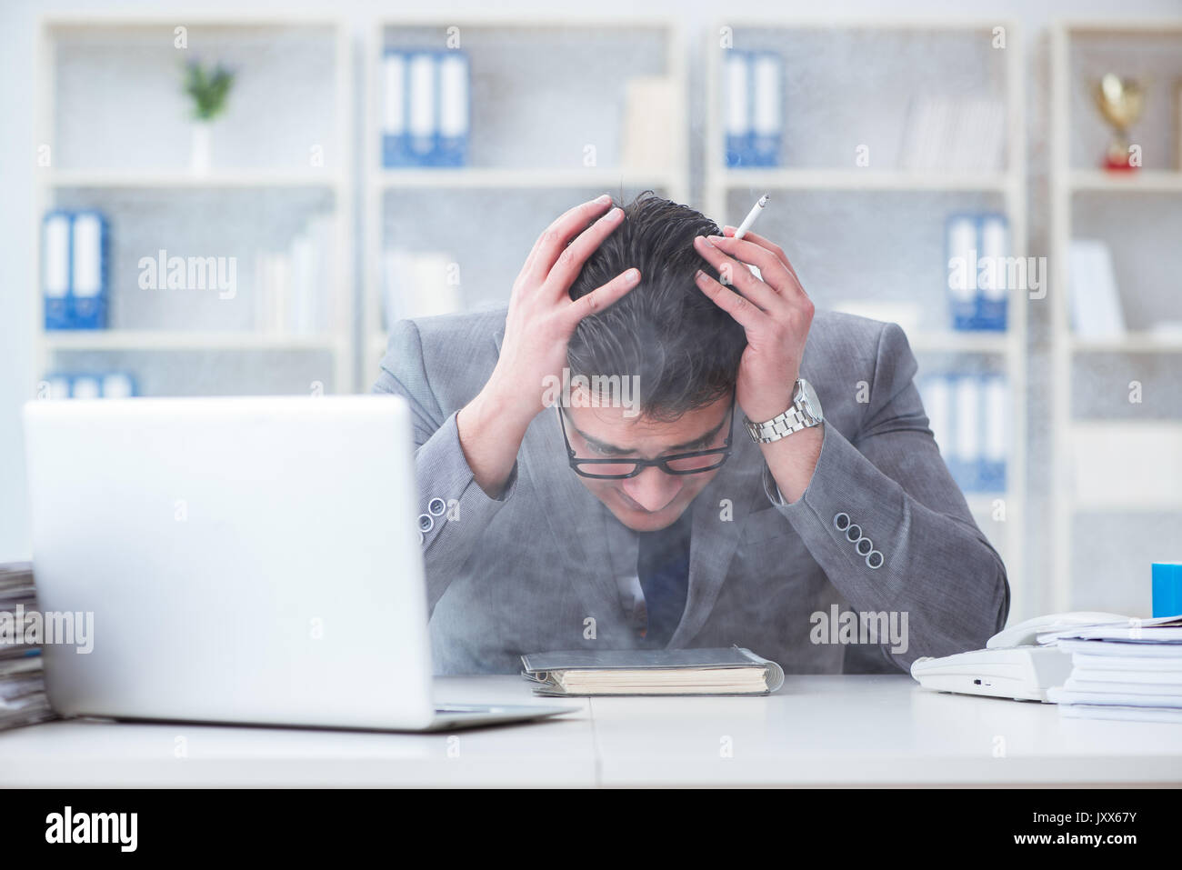 Businessman smoking in office at work Stock Photo - Alamy