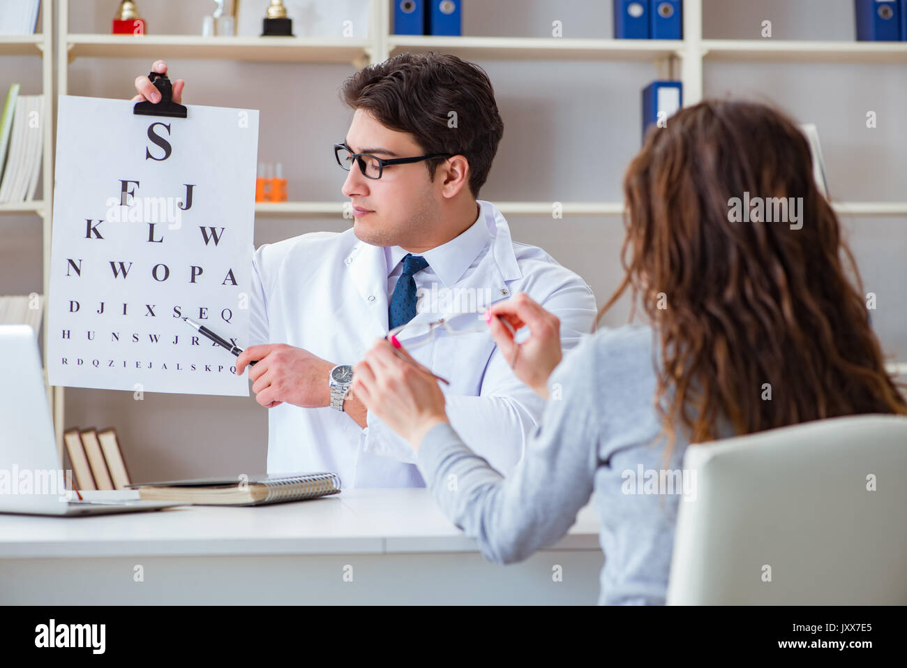 Doctor optician with letter chart conducting an eye test check Stock ...