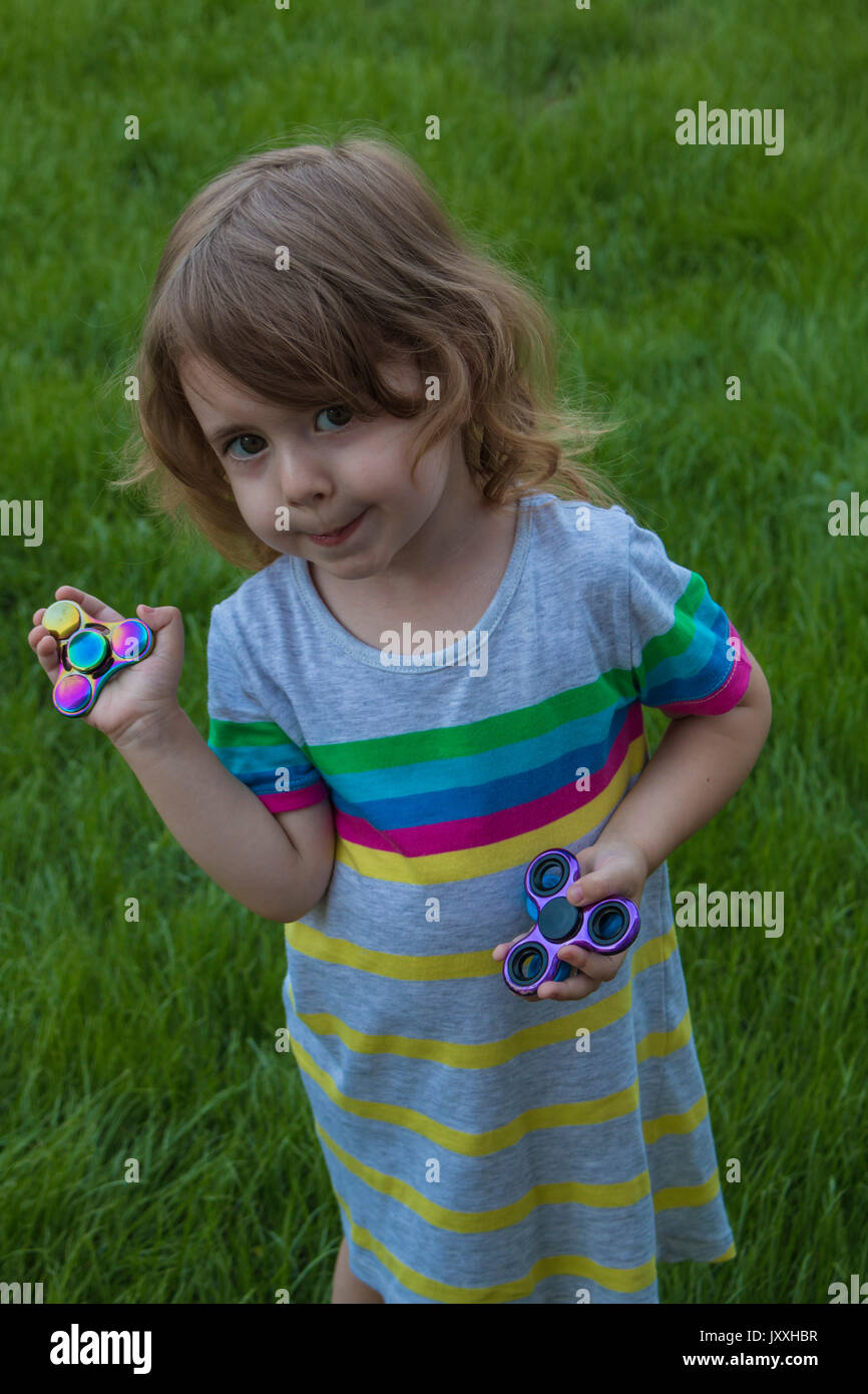 Little beautiful girl is playing with two spinners in hands Stock Photo ...