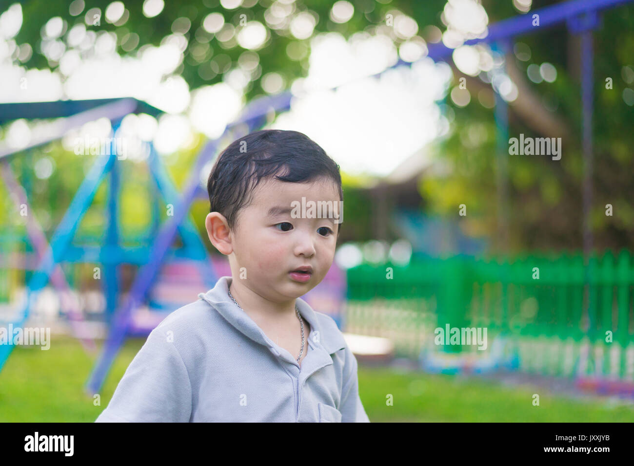 Little Asian kid at the playground under the sunlight in summer ...