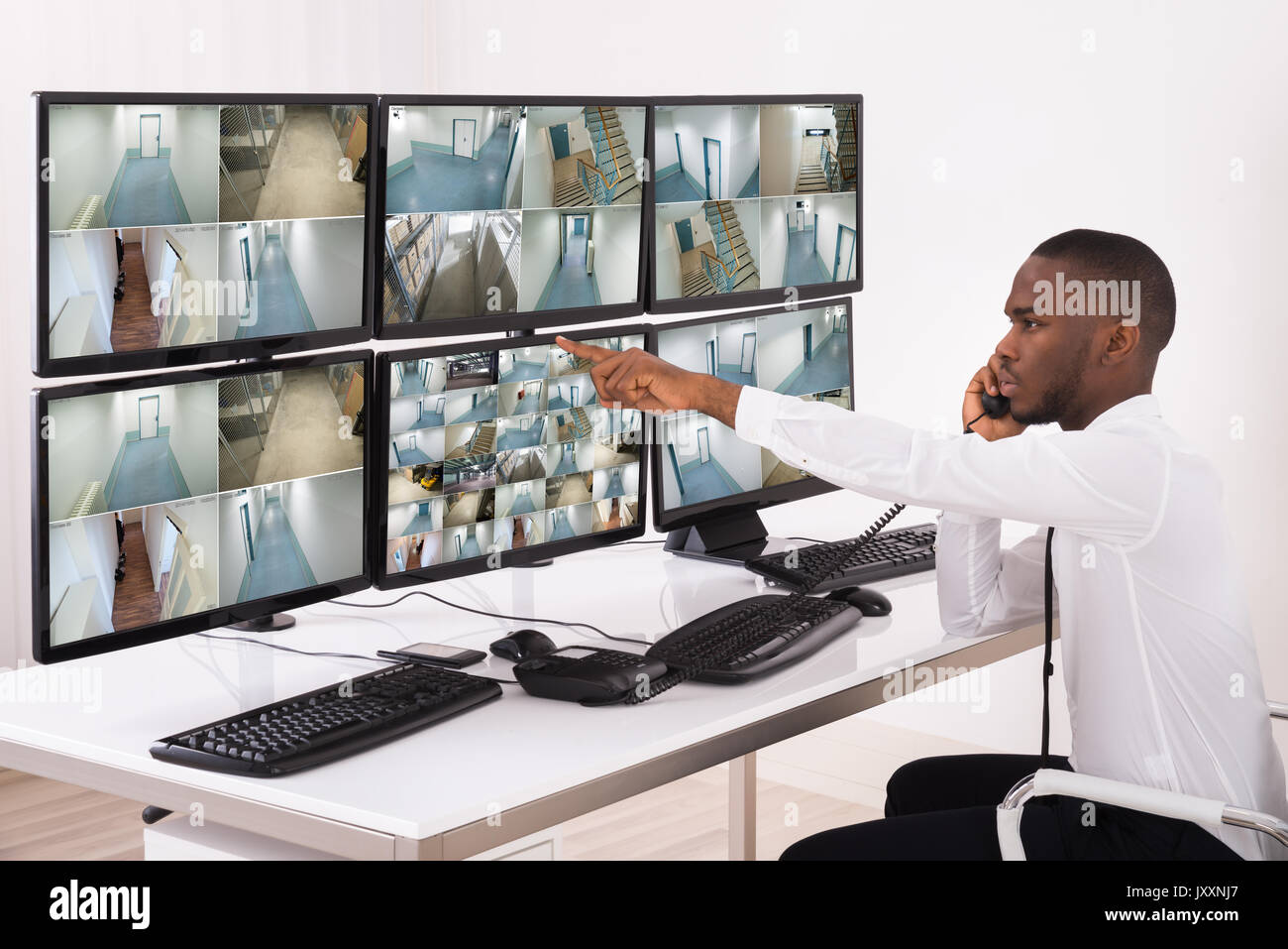 Security System Operator Talking On Phone While Looking At CCTV Footage ...