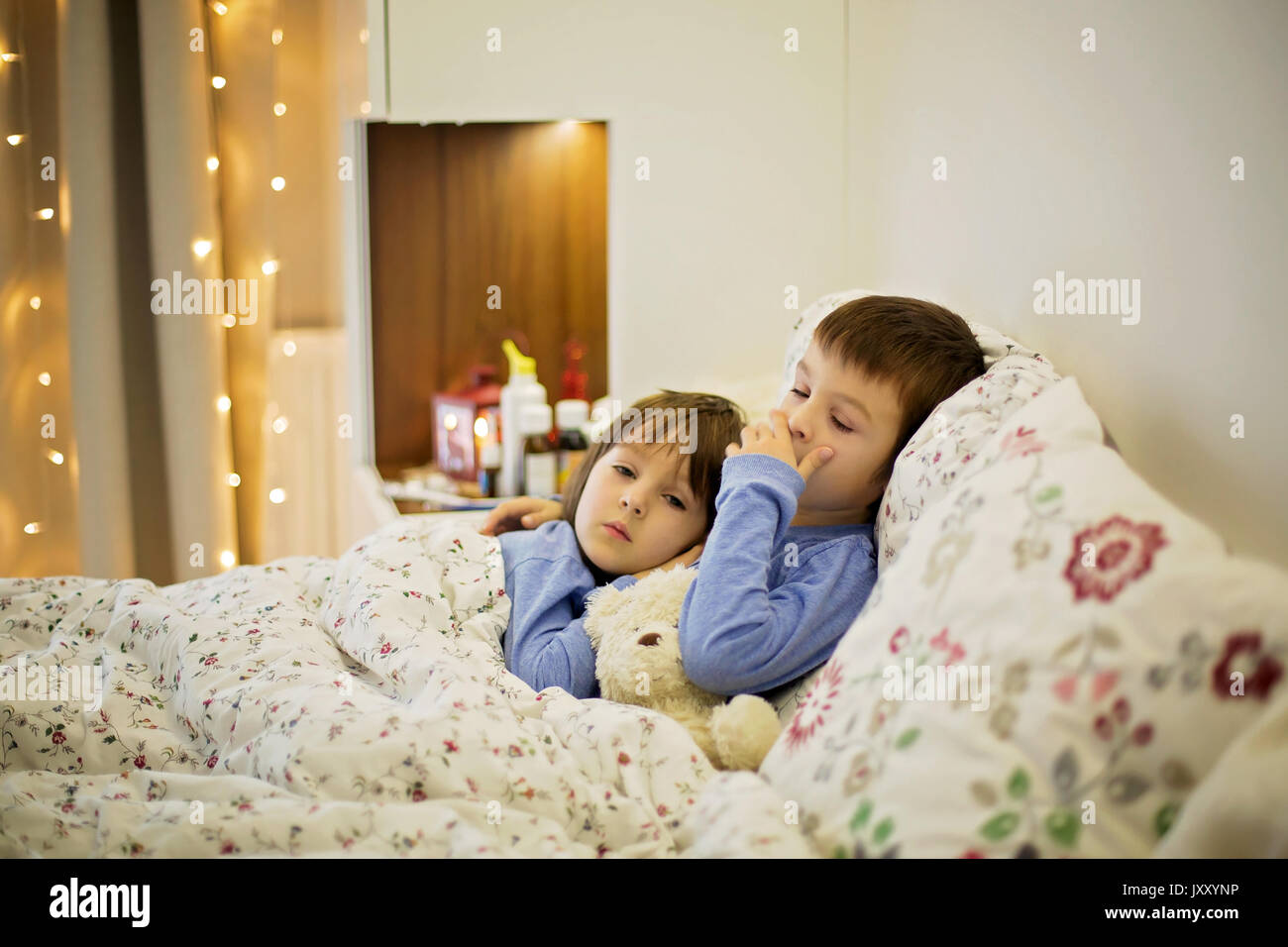 Two cute sick children, boys, staying in bed with fever, playing with ...