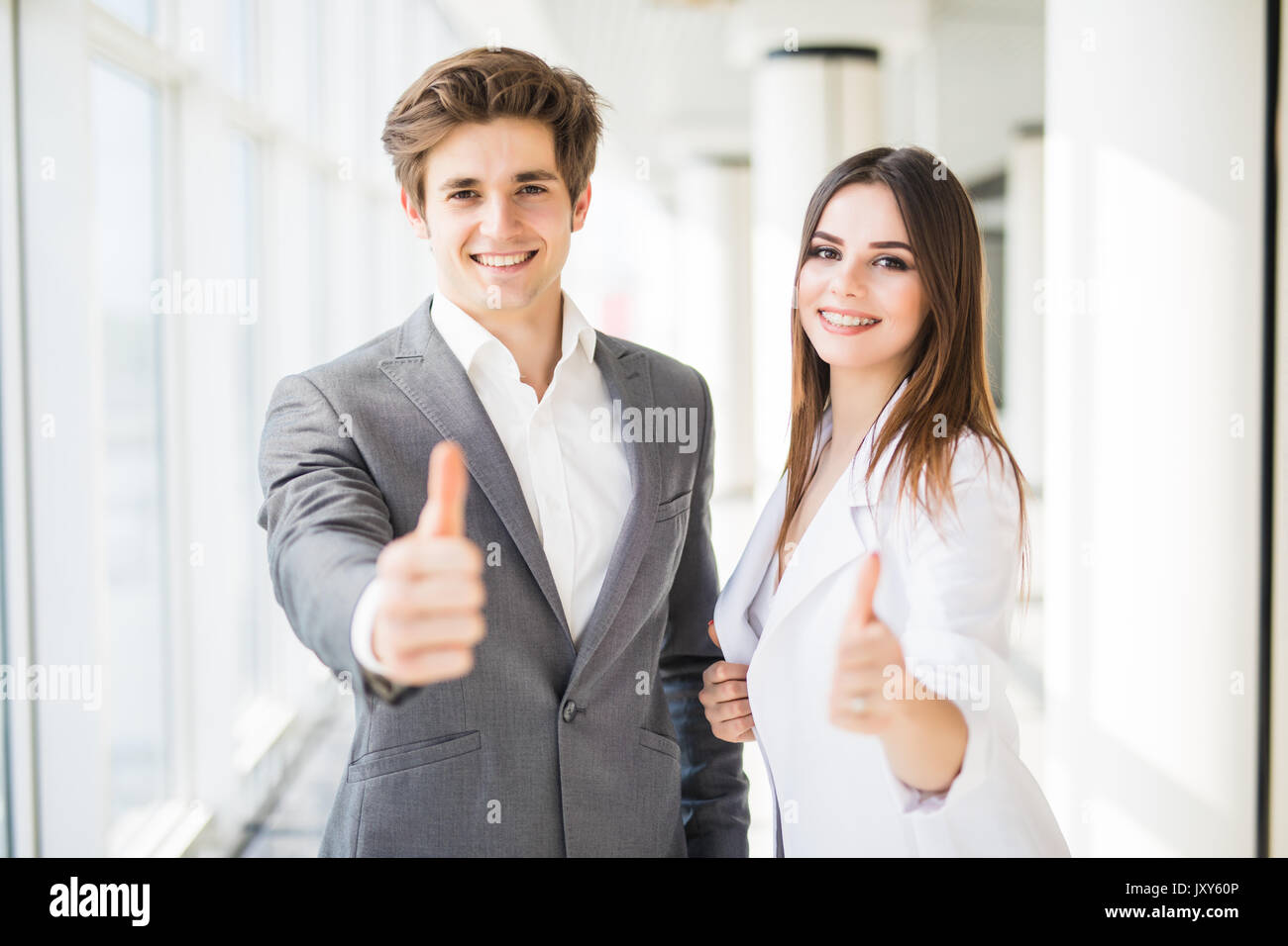Business couple showing thumbs up in business office Stock Photo - Alamy