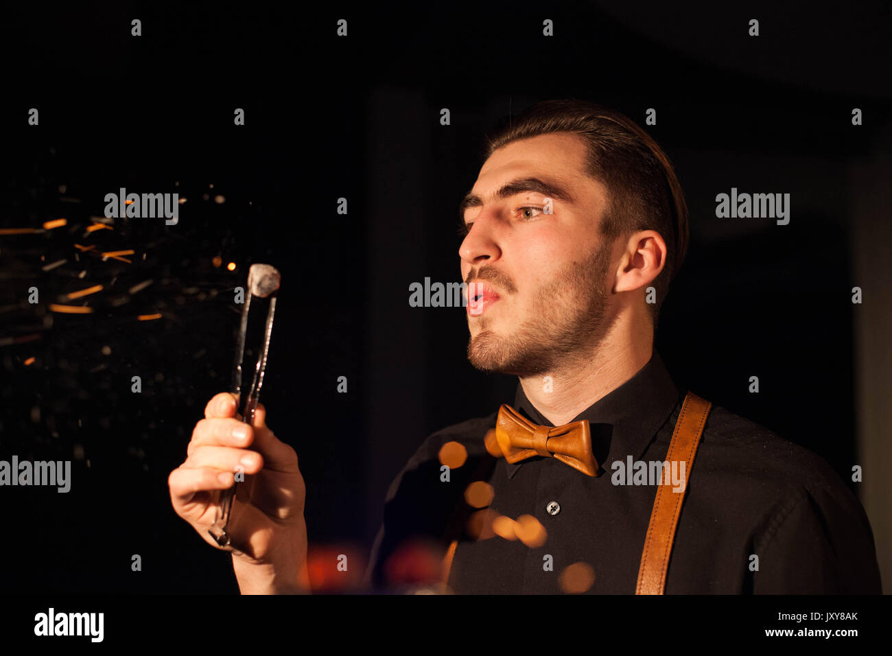 Portrait of a hookah man blowing on a hookah ember. Sparks flying all ...